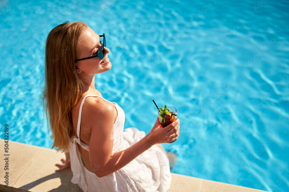 Blonde woman drinks refreshing cocktail sunbathing and sitting near ...