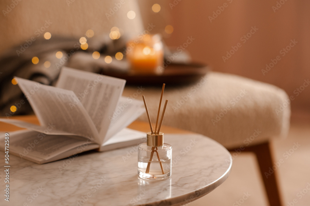 Liquid home fragrance in diffuser with open paper book on coffee table ...