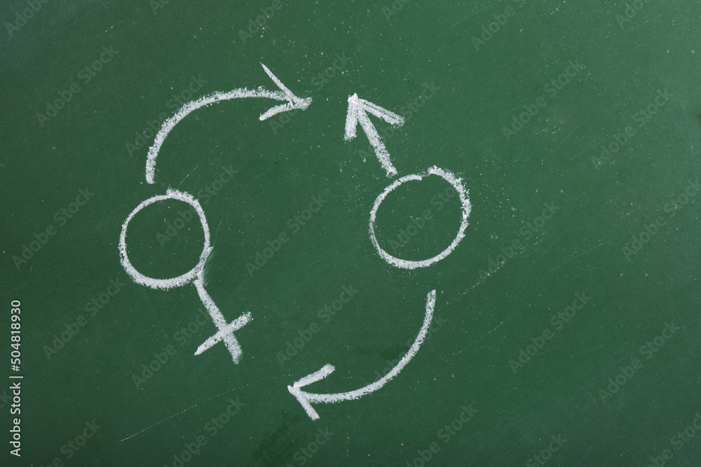 gender symbols with arrows drawn in chalk on a green chalk board ...