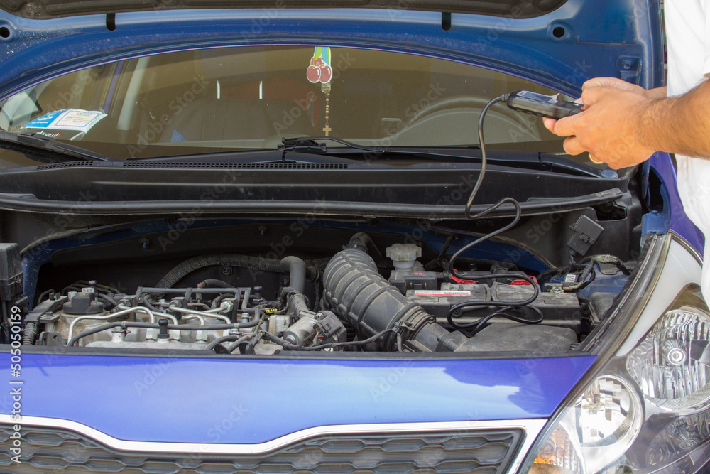Mechanic who in his workshop checks the parameters of the engine of a ...