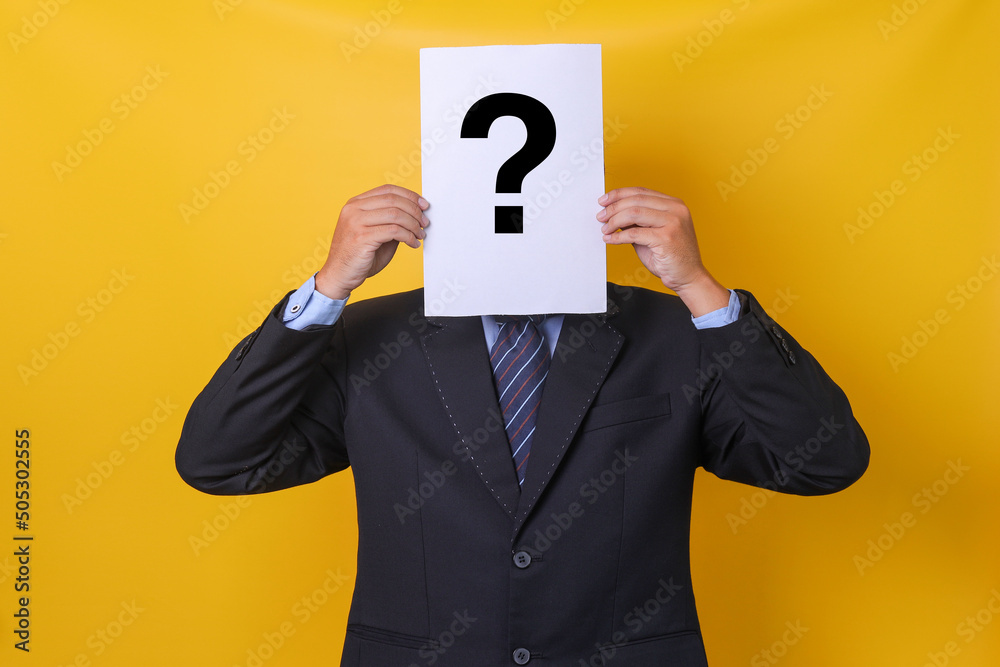 Businessman covering his face with a white paper with big question mark ...