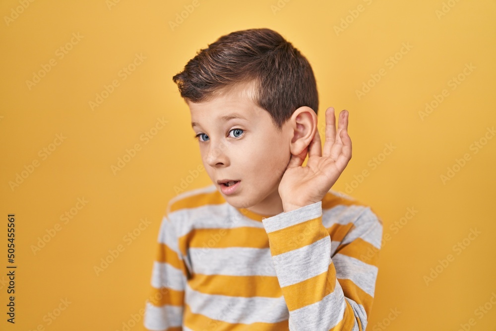 Young caucasian kid standing over yellow background smiling with hand ...