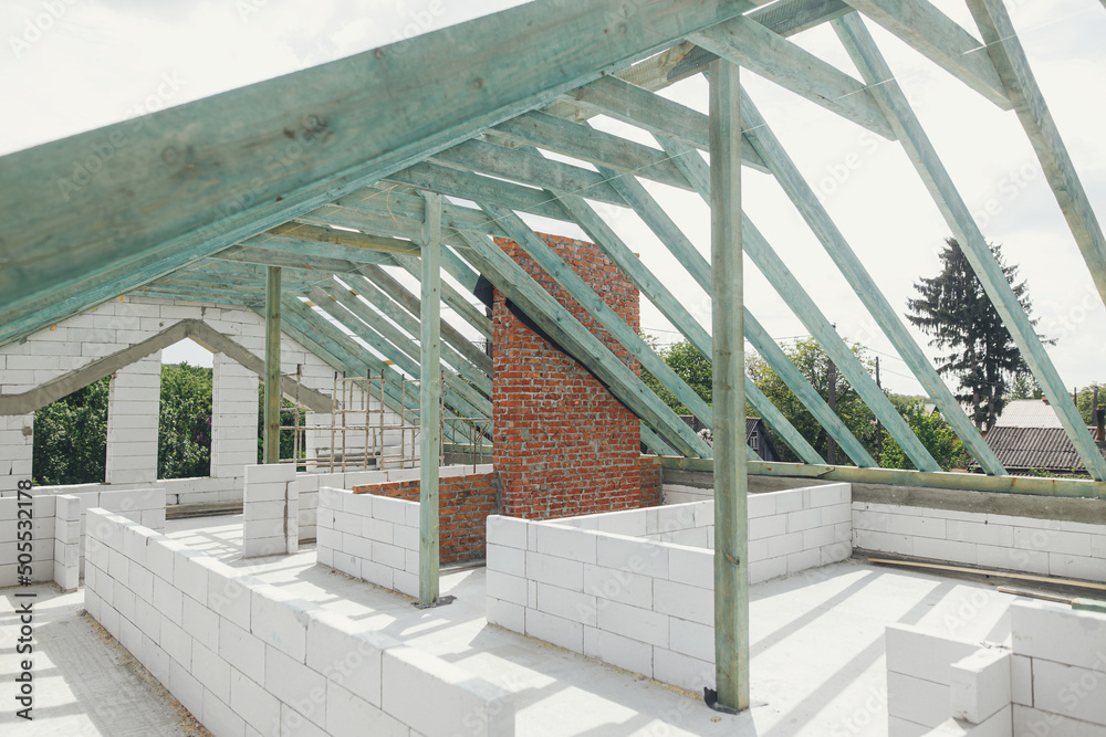 Wooden roof framing. Unfinished roof trusses and aerated concrete block ...