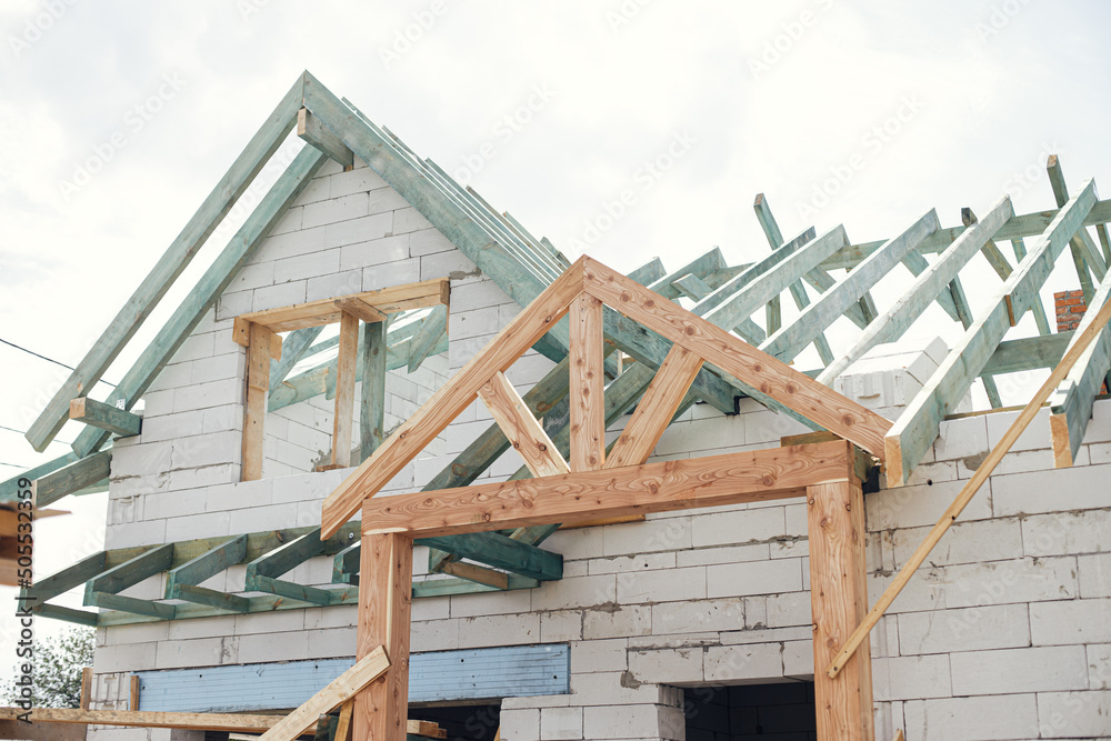 Unfinished modern farmhouse building. Wooden roof framing of mansard ...