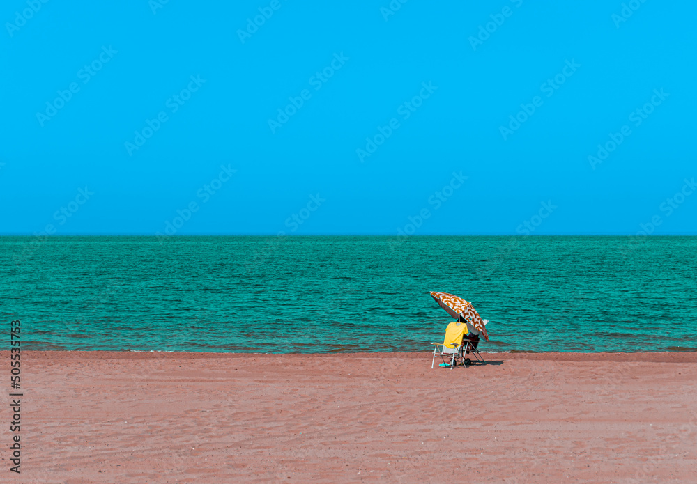 White sand beach, with an umbrella and a beach chair, calm sea, clear ...