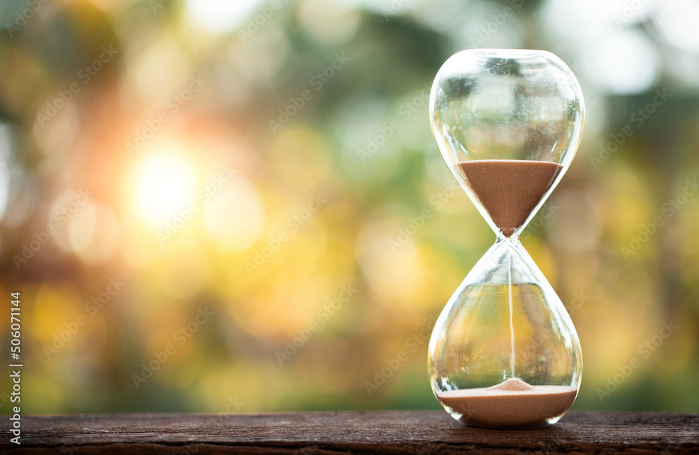 hourglass (sand clock) on an old wooden table with a natural blur ...