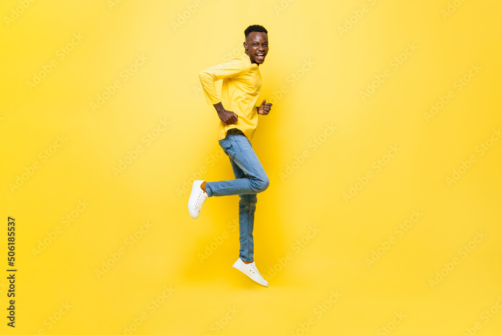Full length portrait of excited African man jumping in isolated yellow ...