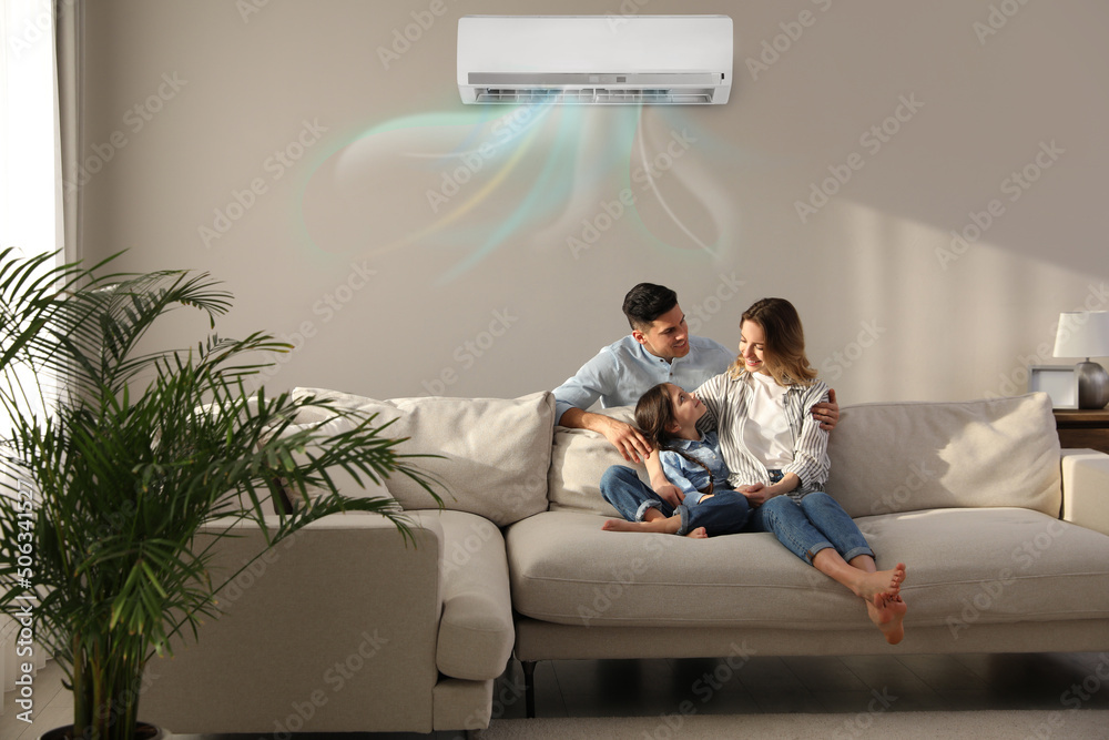 Happy family resting under air conditioner on beige wall at home Stock Photo | Adobe Stock