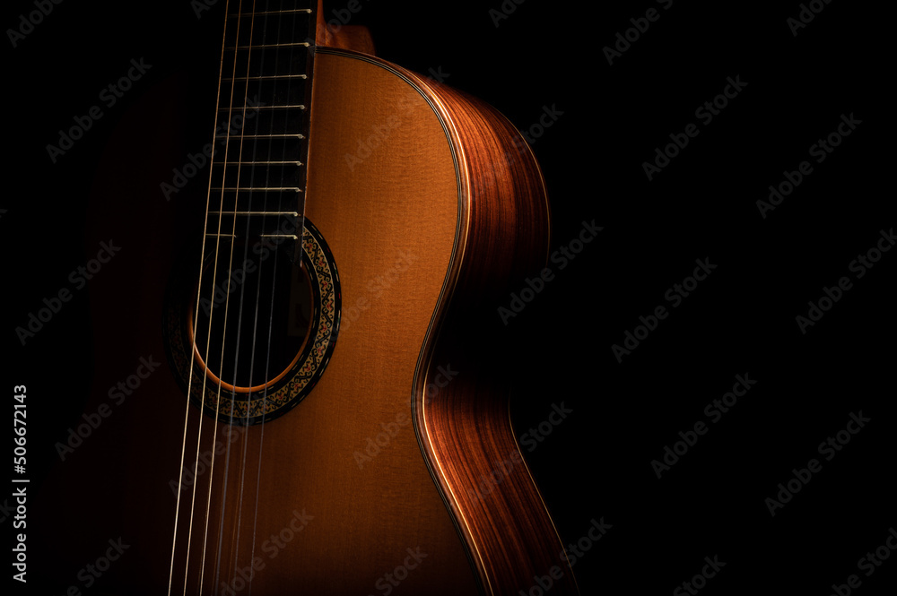Classical guitar close up, dramatically lit on a black background with ...