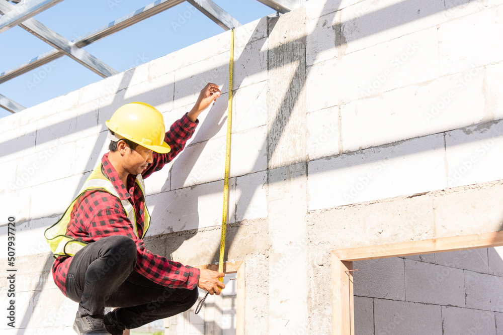 Construction worker or contractor man using measuring tape checking ...