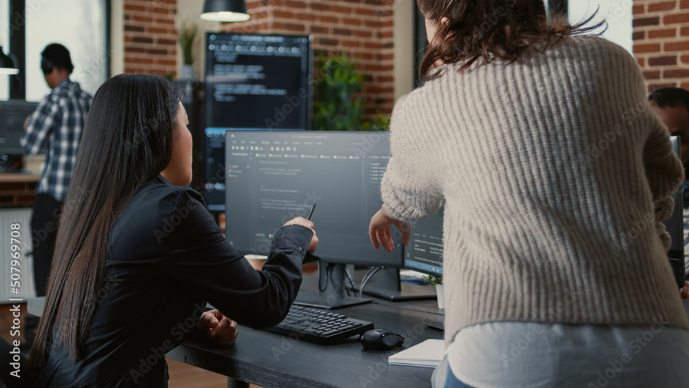 Programer pointing pencil at computer screen with software compiling code explaining source ...