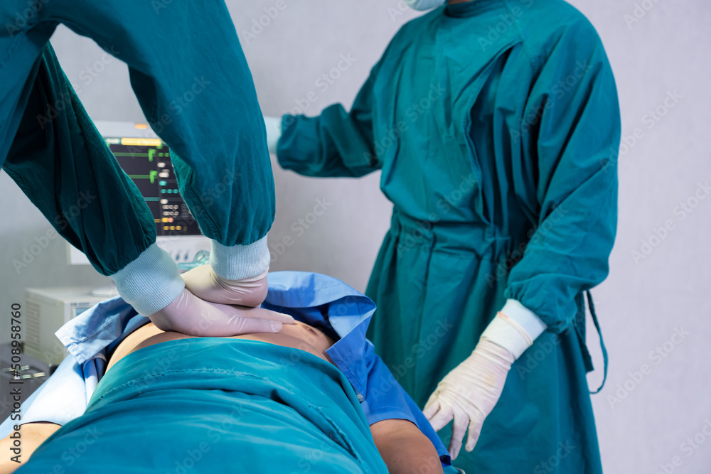 Foto de Stock Doctor and nurse using defibrillator to pump at chest of unconscious with low ...