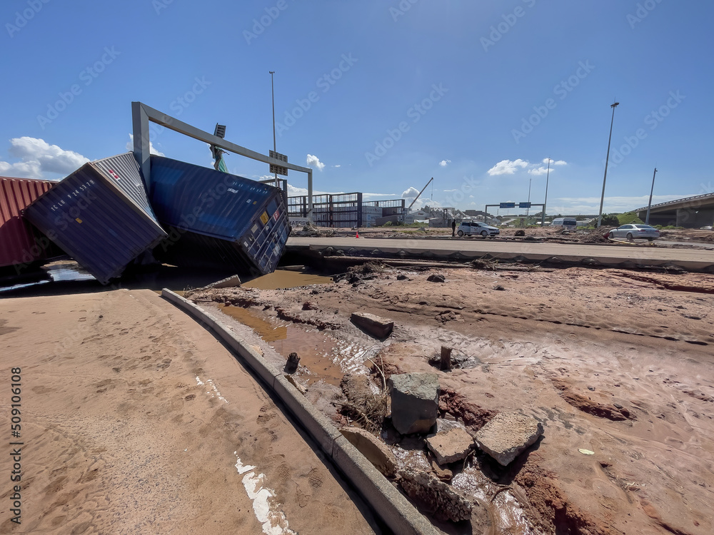 A view of a shipping container, lying in mud and debris, that has ...