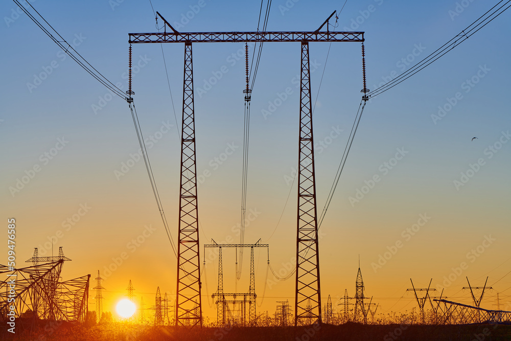 Sun rise on field with high voltage electricity towers. Dark ...