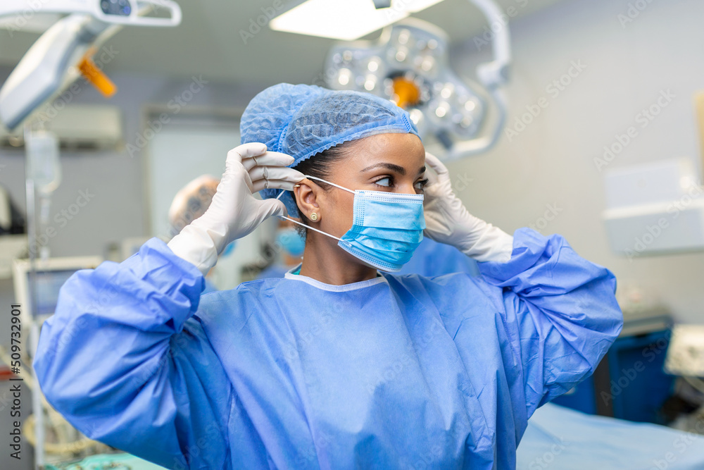 Portrait of beautiful female doctor surgeon putting on medical mask ...