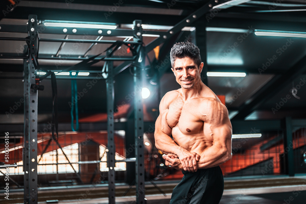 Bodybuilder with a perfect physique poses, showing off his biceps, abs ...