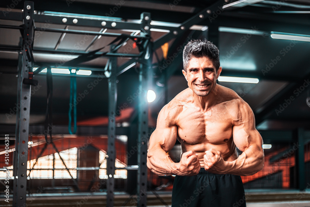 Bodybuilder with a perfect physique poses, showing off his biceps, abs ...