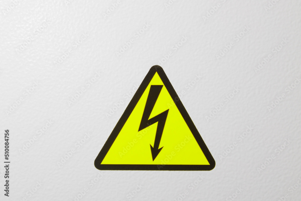 High voltage light green triangle warning sign on gray metal wall ...
