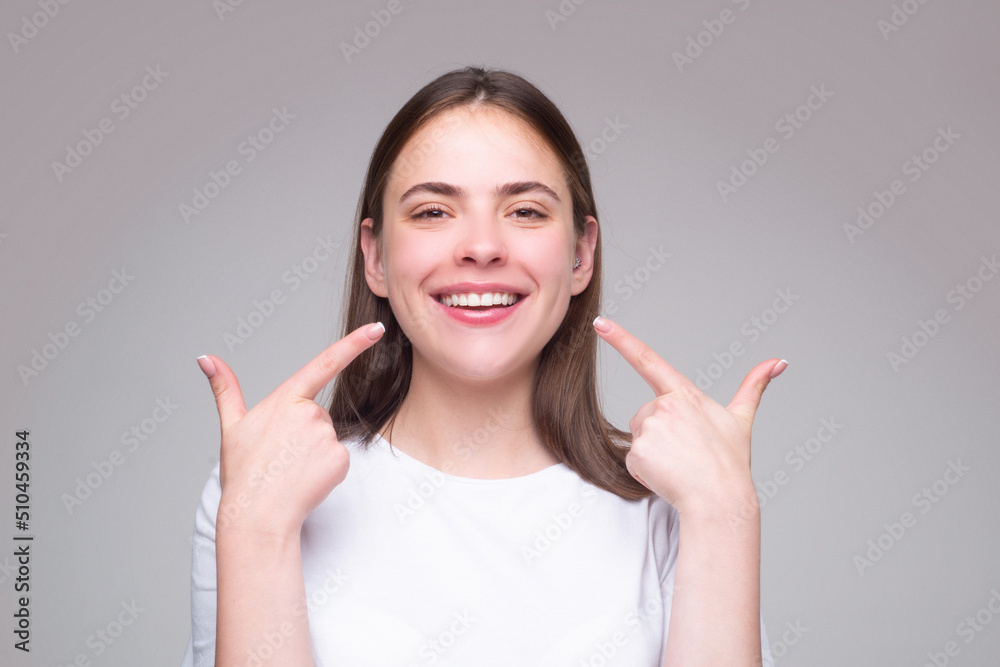 Beautiful woman pointing to teeth. Beautiful smile with white teeth. Closeup smiling woman mouth ...