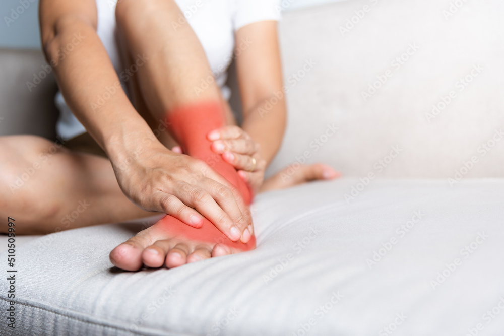 Foot pain, Asian woman sitting on sofa hold her ankle injury feeling ...