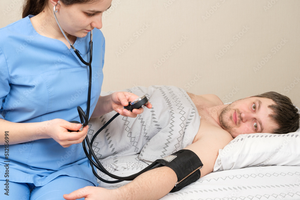 The doctor measures the blood pressure of a young 30-year-old man lying ...