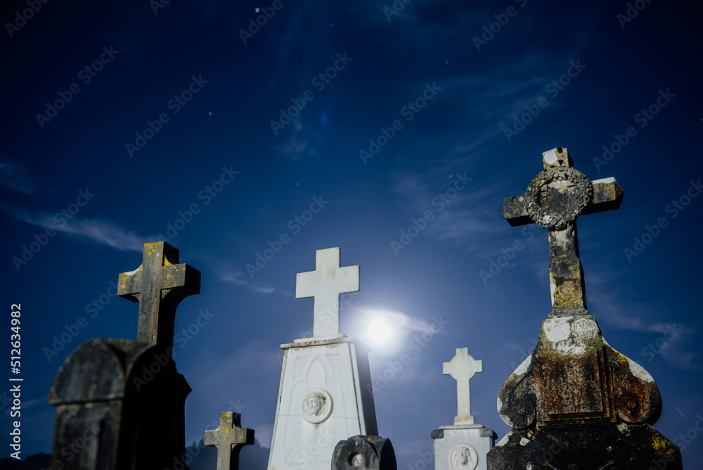 tombs with Christian crosses in a cemetery at night with a full moon ...