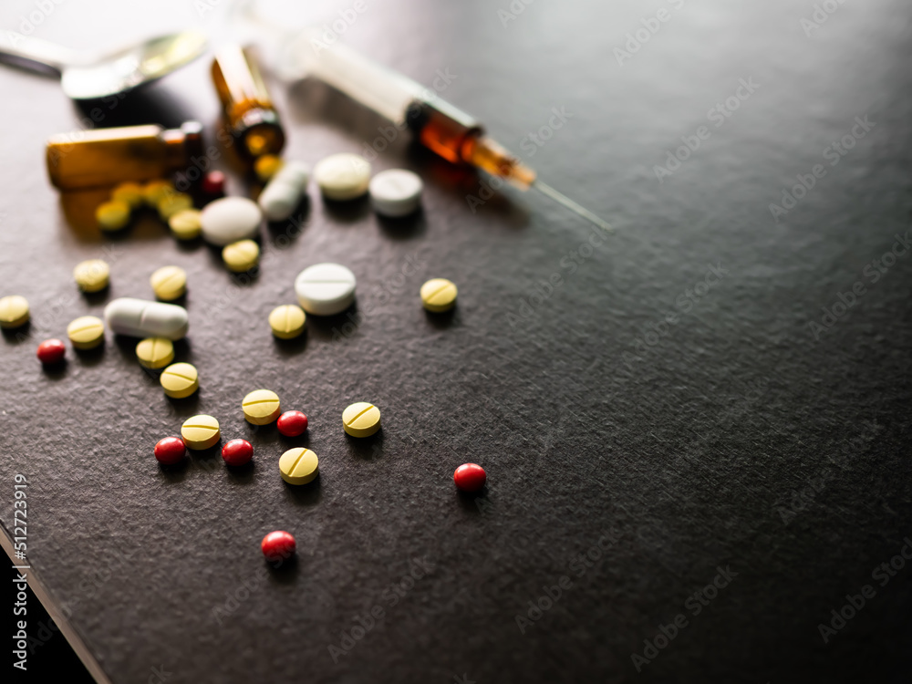 Narcotics concept. Ecstasy Pills and syringe on black wooden table ...