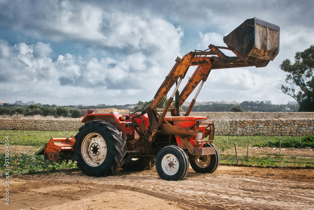 Agricultural tractor with digger and ploughing attachment at the back ...