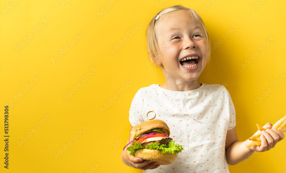 Cute little caucasian girl with blonde hair enjoying burger on a yellow ...