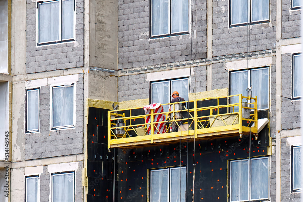 Foto Insulation facade wall with mineral wool. Worker on suspended ...