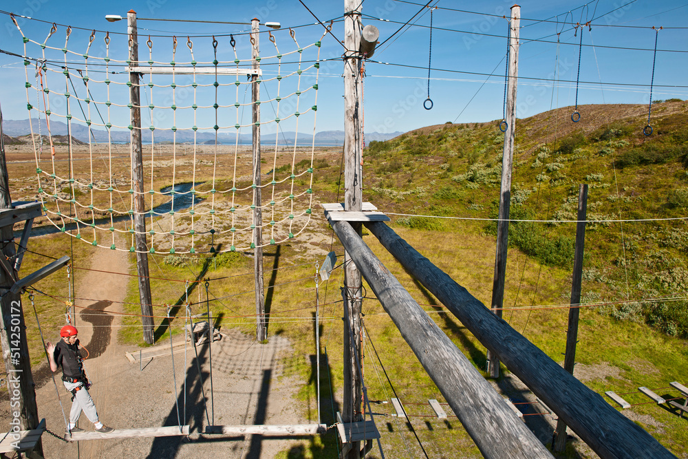 teenage boy balance on plank at high rope playground in Iceland Stock ...