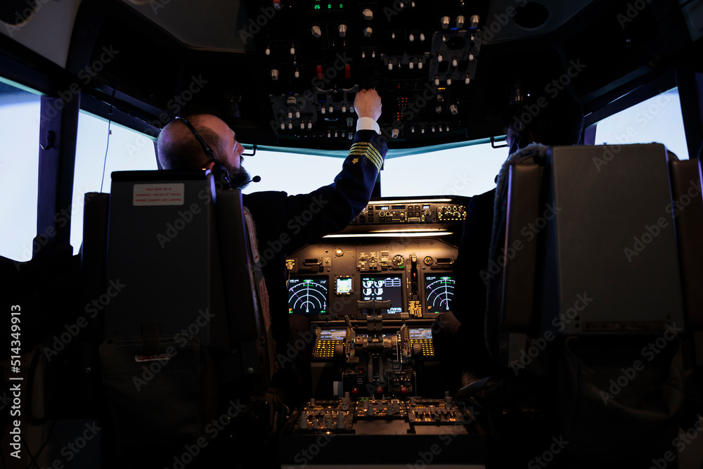 Captain and african american pilot flying aircraft jet in cabin using ...