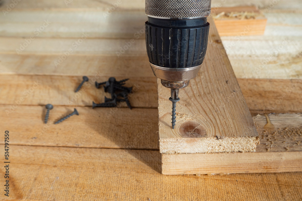 Screwing screws into wooden boards. Self-tapping screws, a screwdriver ...
