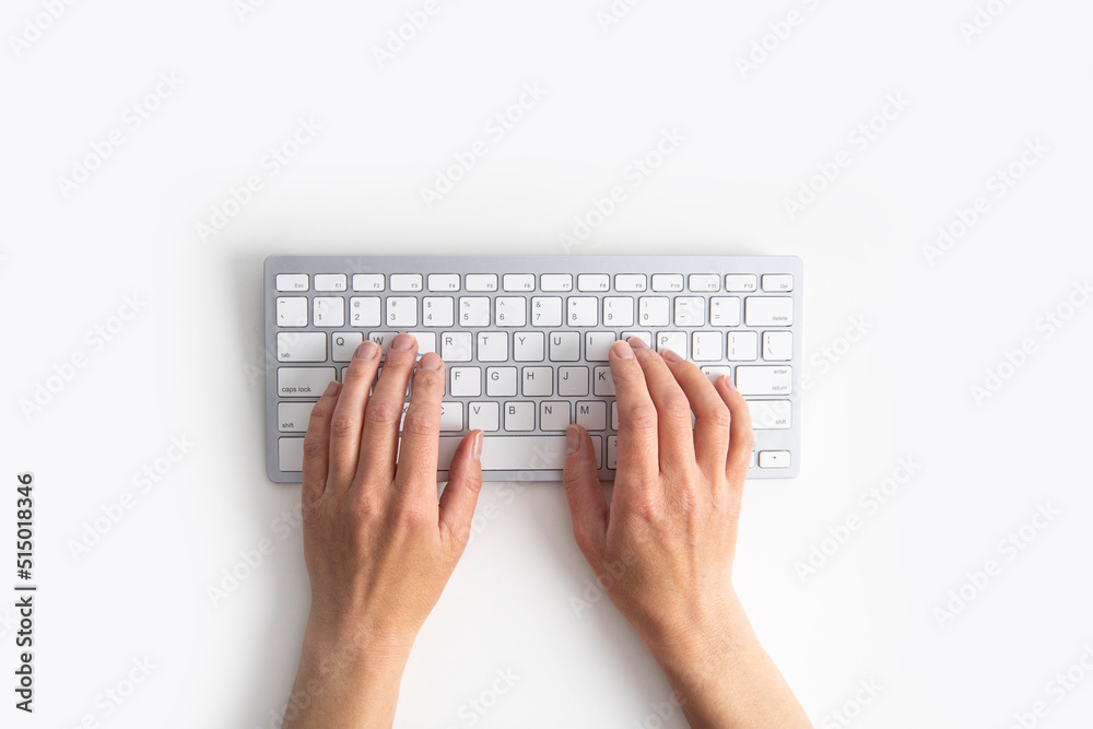Female hands on the keyboard on a white background. Top view, flat lay ...