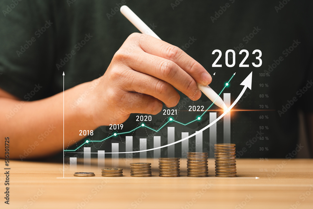 Businessman planning 2023 business growth on desk with virtual hologram ...