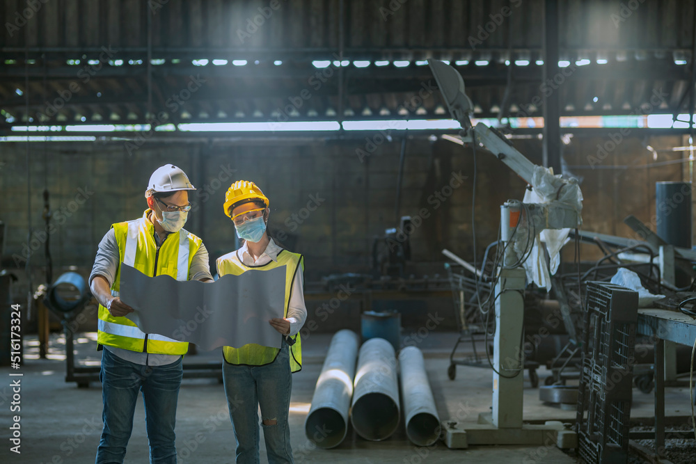 male and female engineers laying out a plan inside the factory to plan the installation of new ...