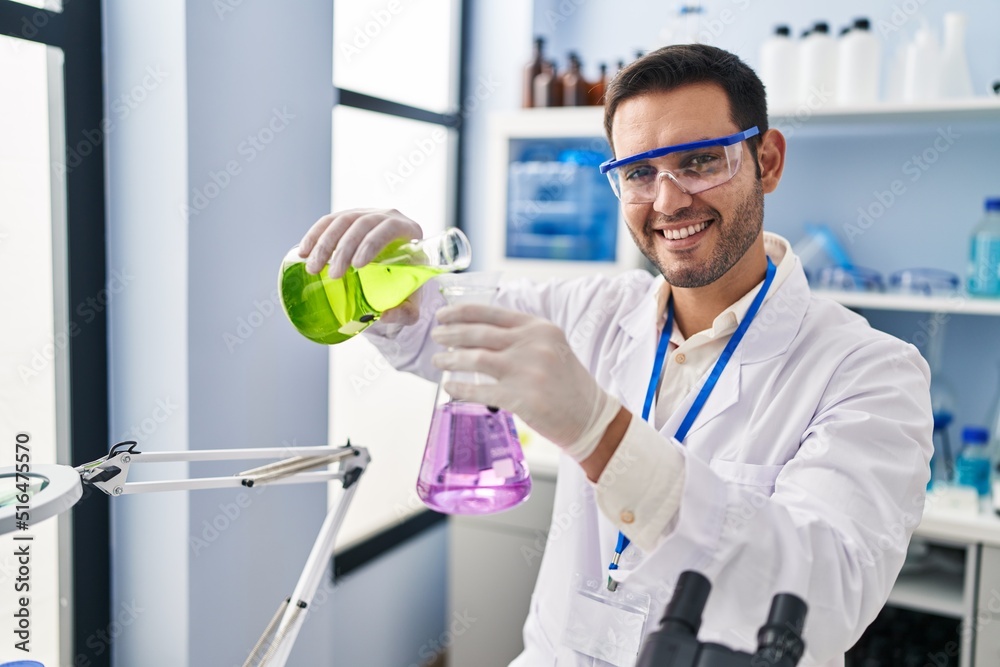 Young hispanic man scientist measuring liquid at laboratory Stock Photo ...