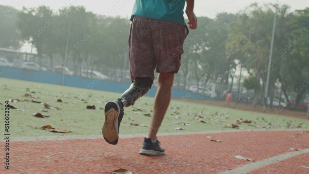 Disabled Athlete running with prosthetic leg at running track ...