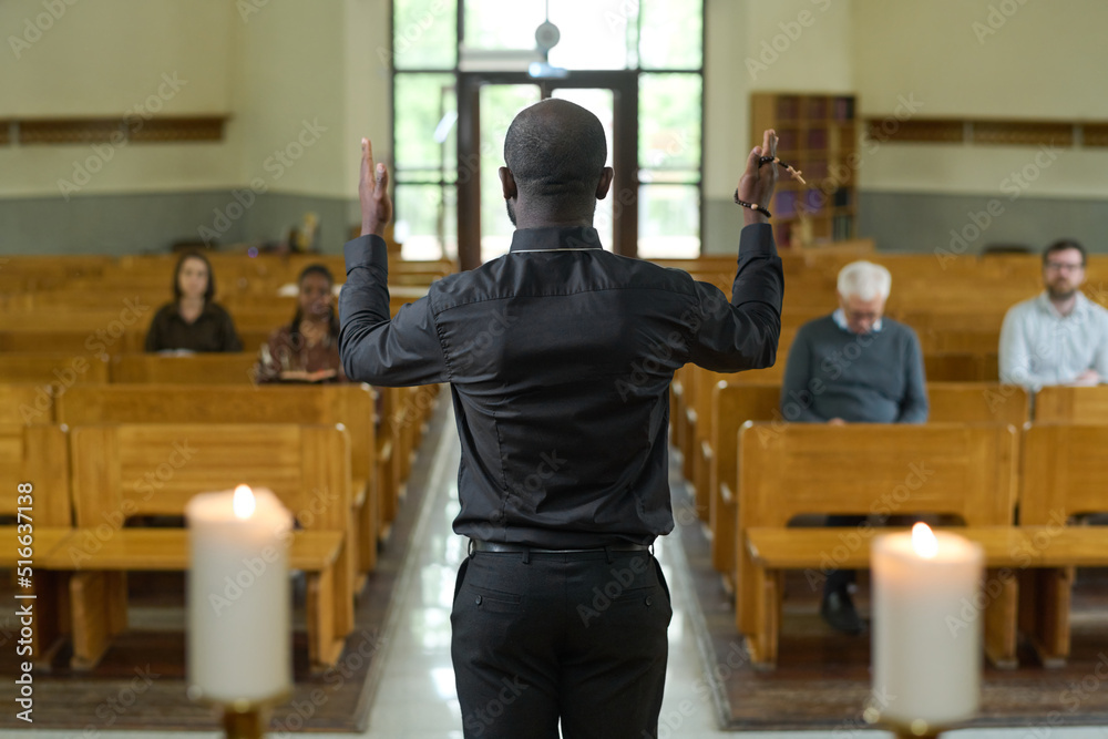Rear view of young African American priest in black shirt and pants ...