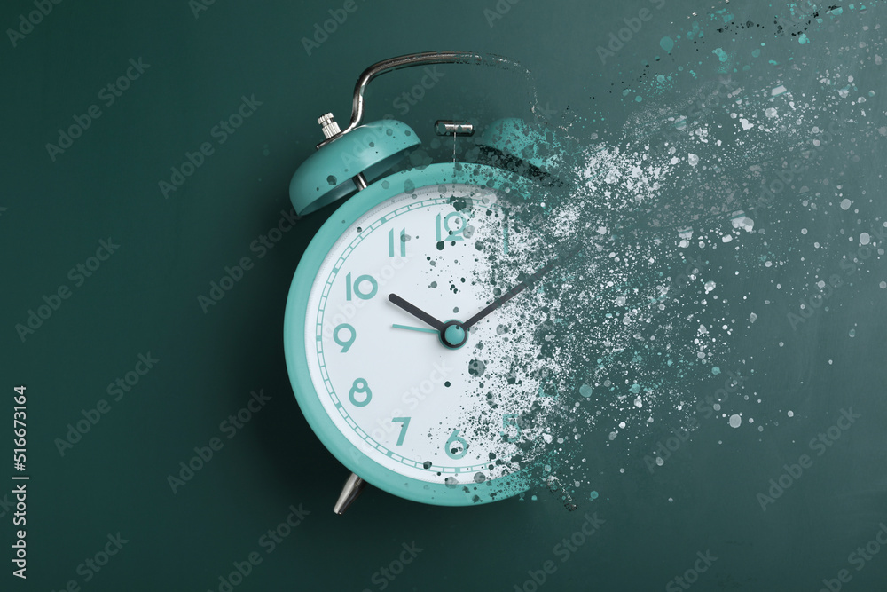 Time is running out. Turquoise alarm clock vanishing on green ...