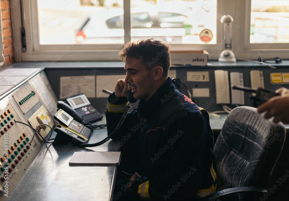 Firefighter on a phone call in the fire house Stock Photo | Adobe Stock