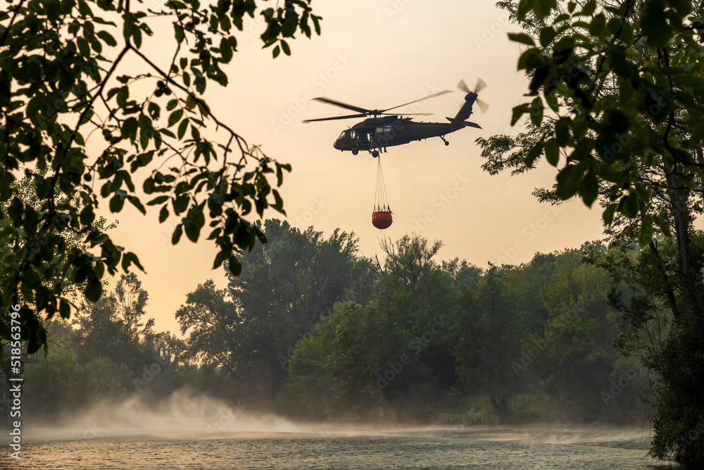Military Helicopter Loading Water from a River for Firefighting a Large ...