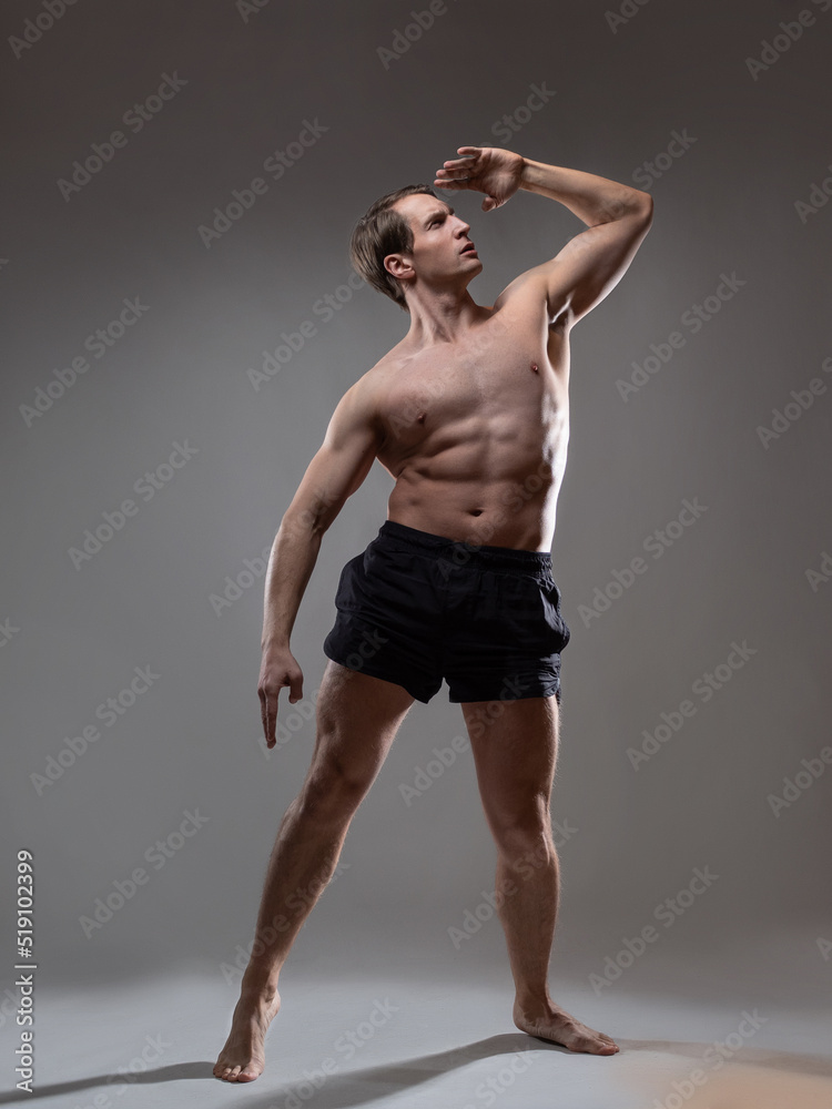 Muscular man in an artistic pose, portrait on a gray background. An ...