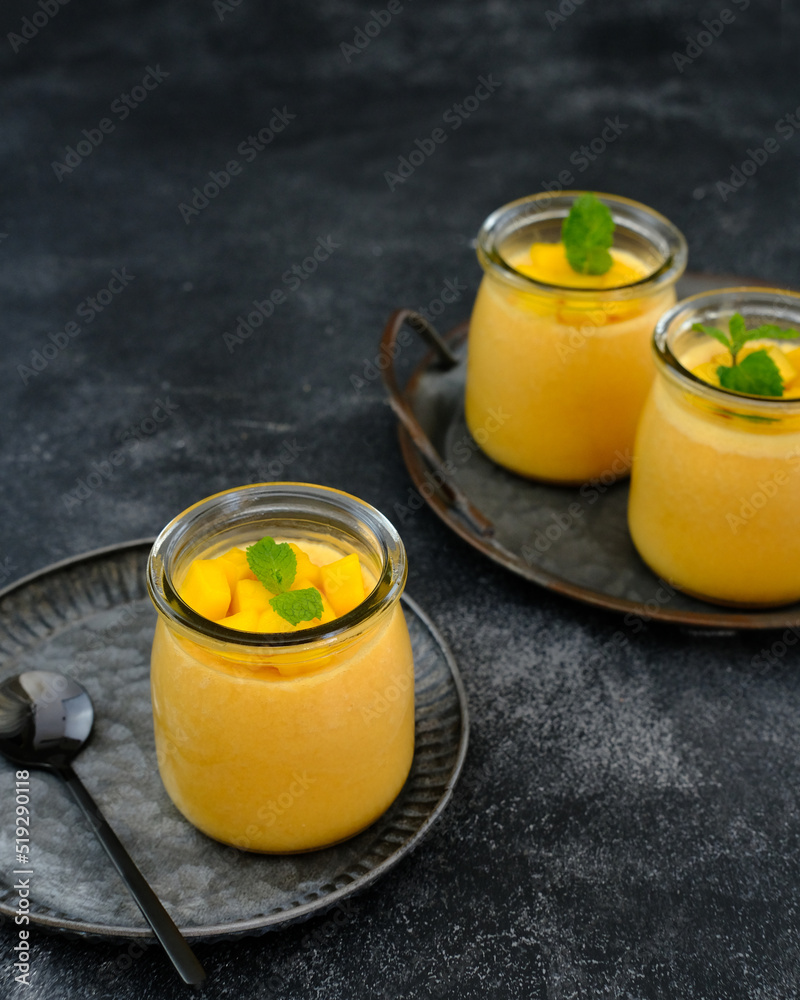 Mango pudding topped with mango chunks and mint leaf garnish. Served in ...