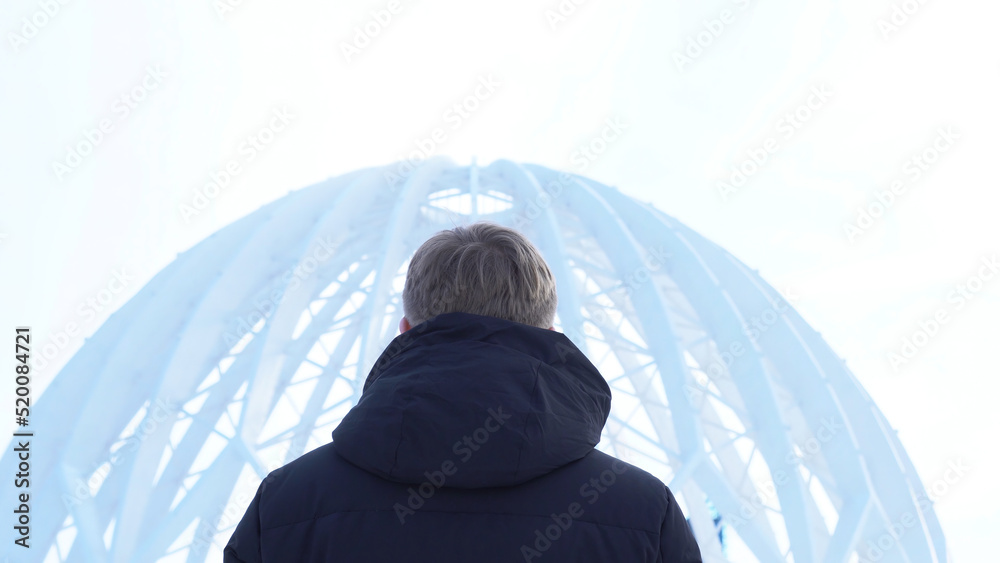Back view of man looking at dome building. Media. View from back of man ...