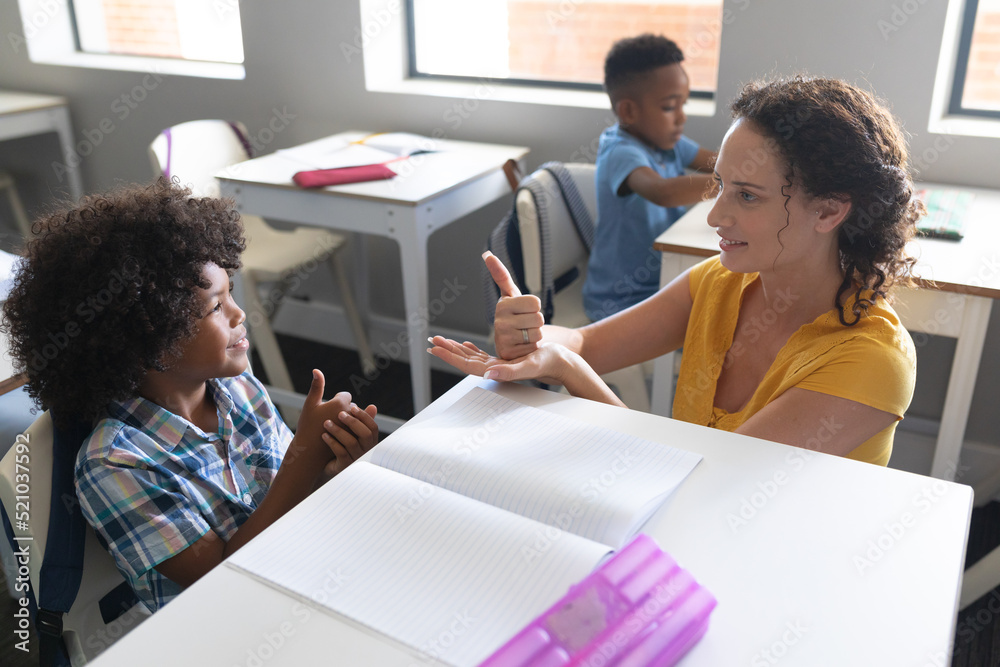 Caucasian young female teacher teaching sign language to african ...
