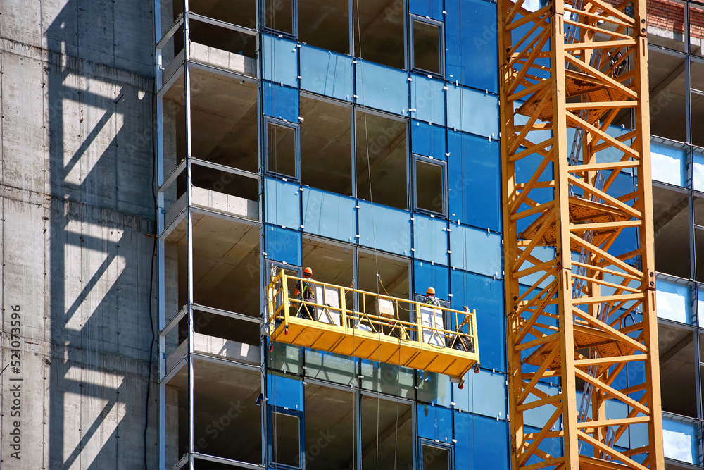 Workers team installing glass windows on building at height ...