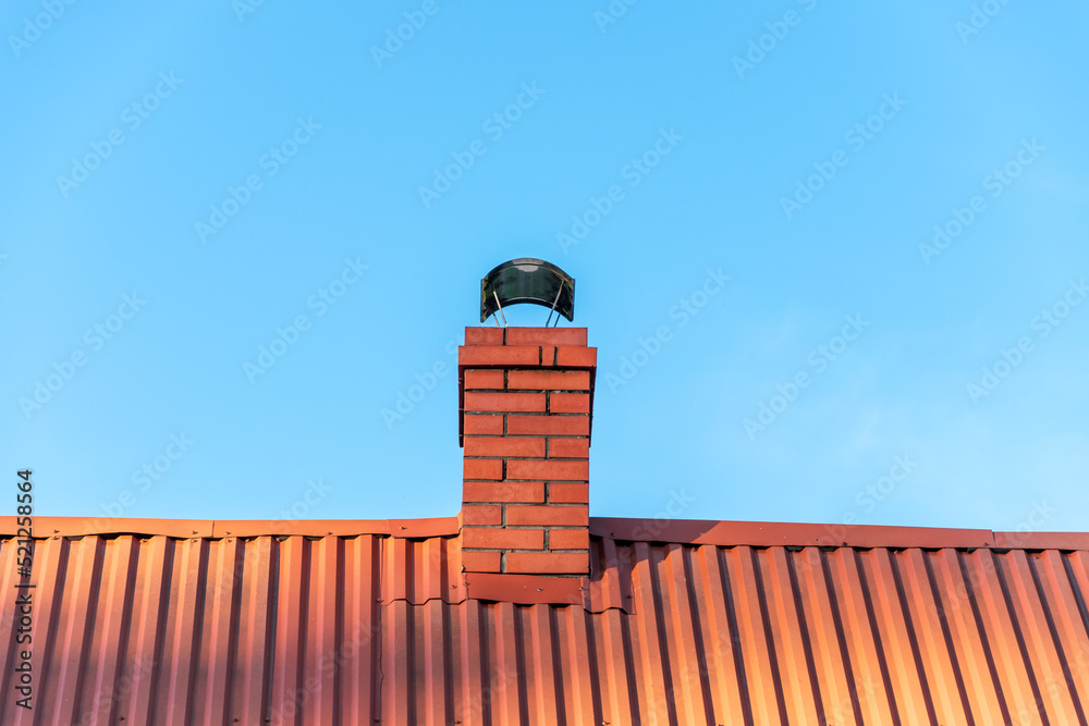 brick chimney made of clinker bricks with a chimney cowl. The roof is ...