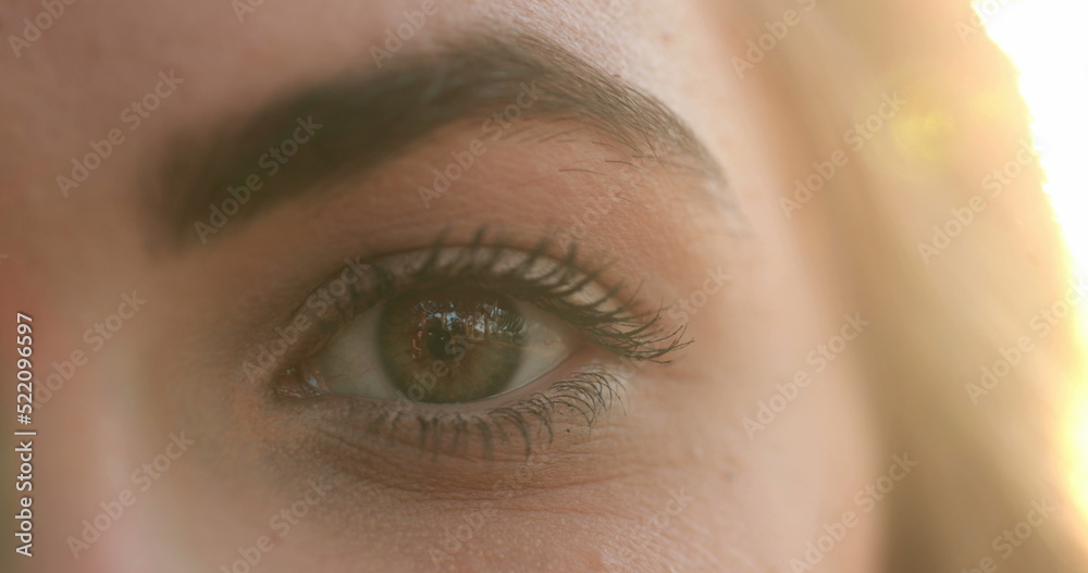 Macro close-up of young woman eyes in the sunlight with flare, opening ...