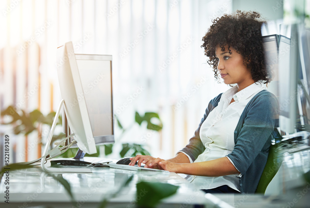 Young female designer working at her computer by a desk in a modern ...